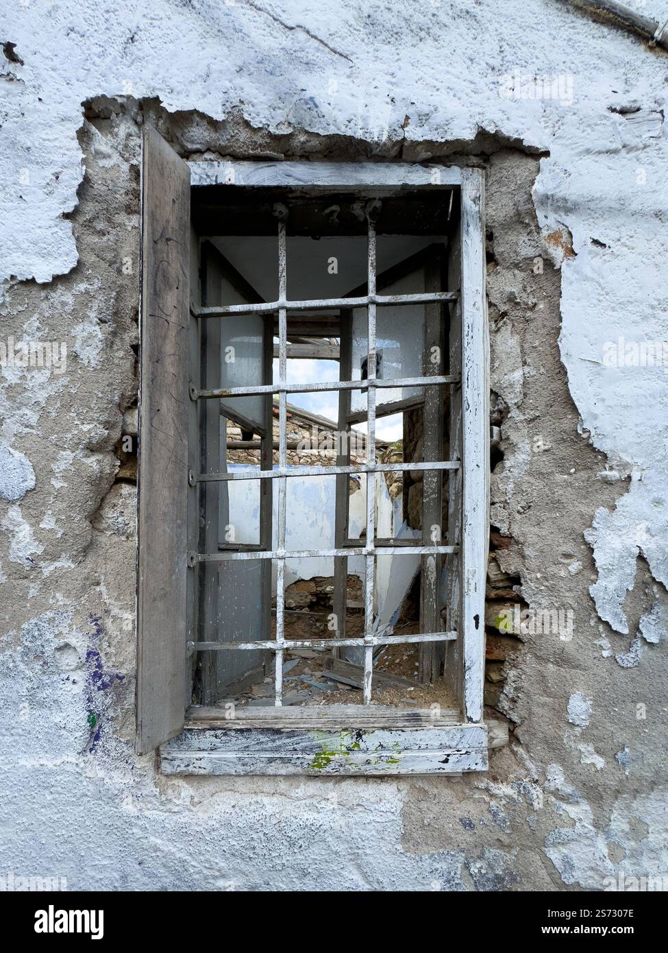 Ruined window with metal bars on an abandoned home facade wall, front ...