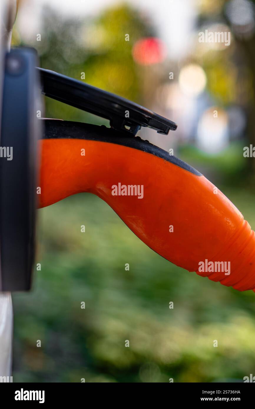 A black and orange electric car charging station. The orange handle is ...