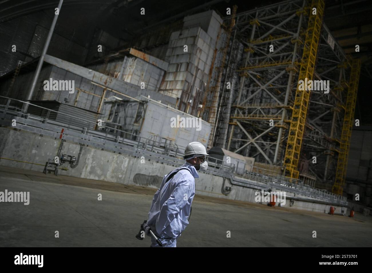 A Technician holding a dosimeter stands next to the destroyed reactor building inside the ...