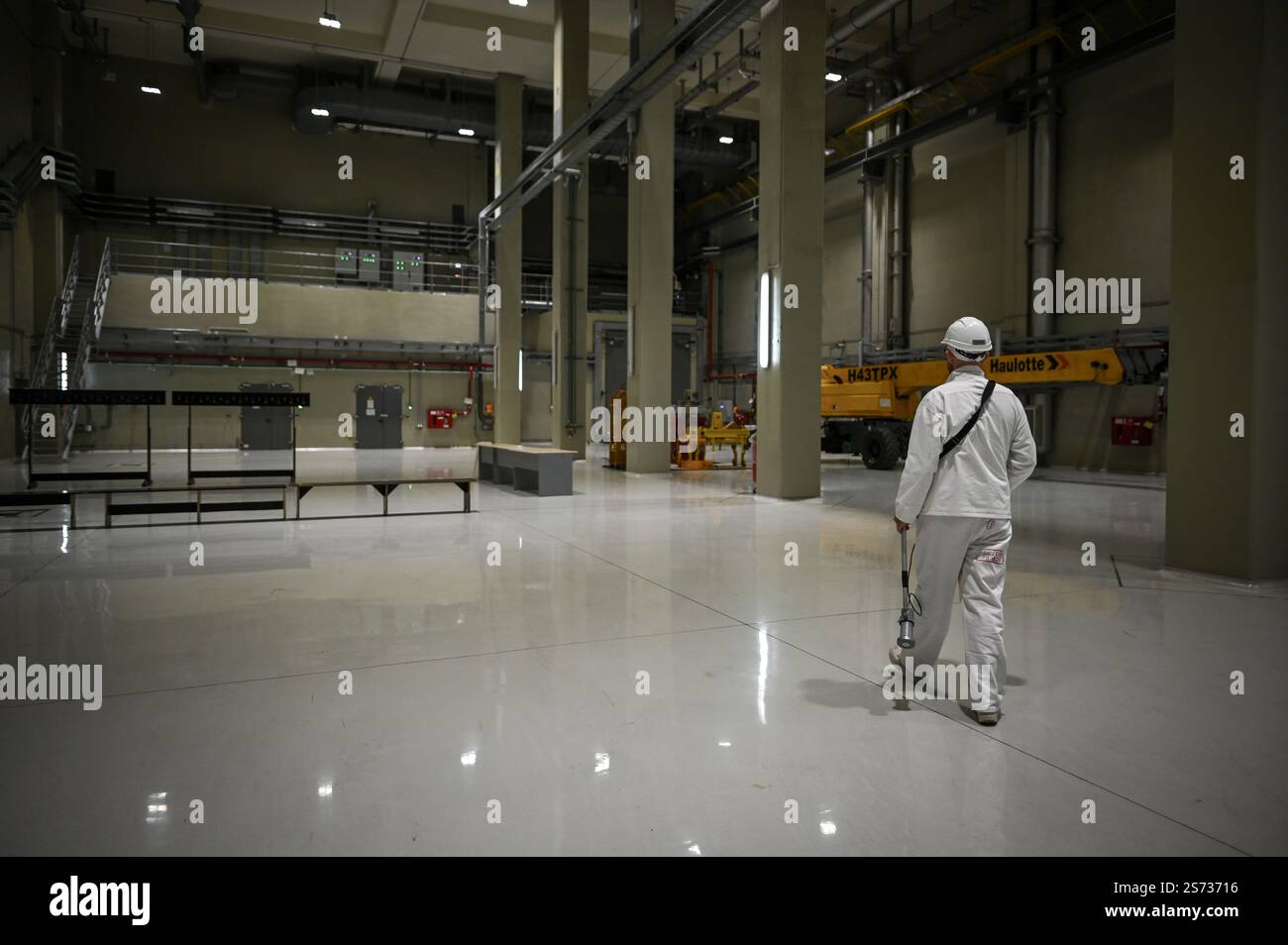 A technician holding a dosimeter walk towards the containment chamber ...