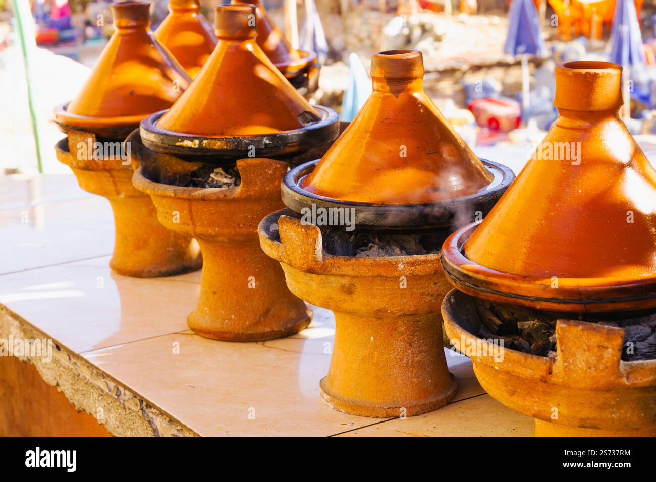 A row of clay pots with lids on a table. The pots are filled with food ...