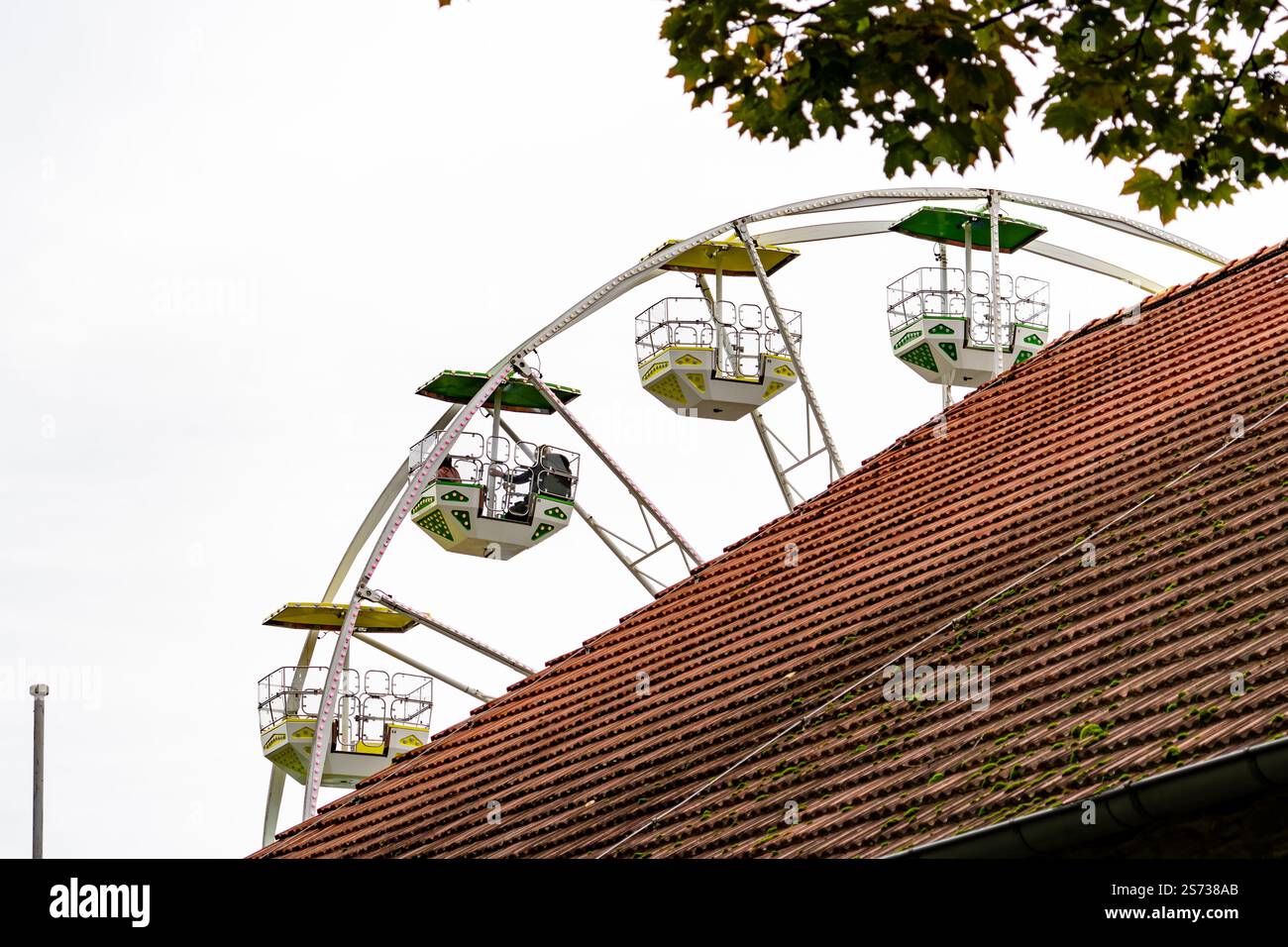 A Ferris wheel with a green canopy is on top of a red roof. The wheel ...