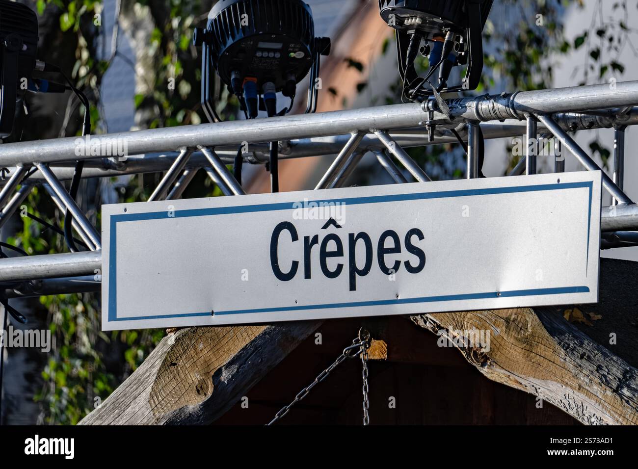A sign with the word crepes written on it. The sign is hanging from a ...