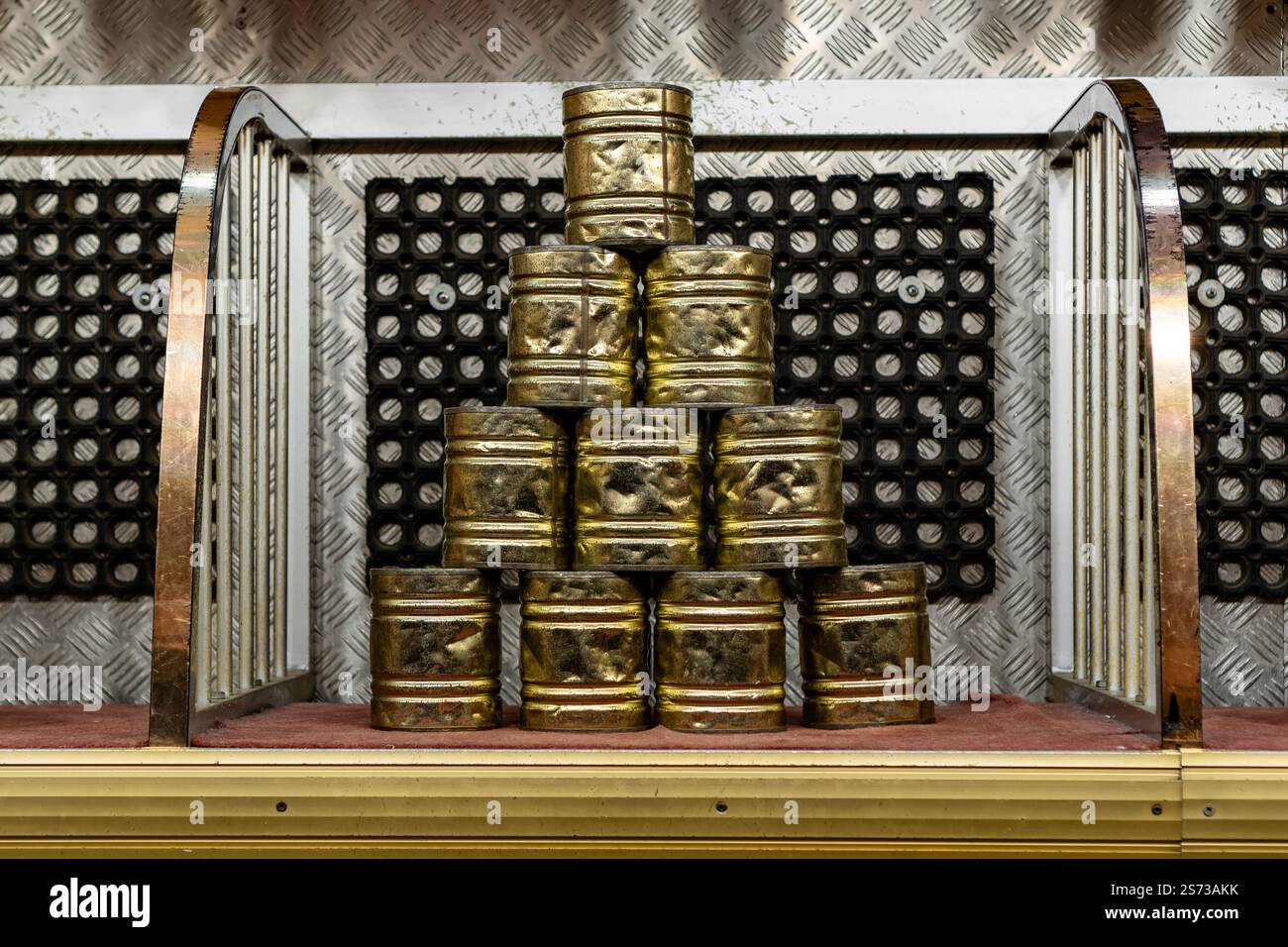 A stack of cans on a shelf. The cans are stacked in a pyramid shape ...