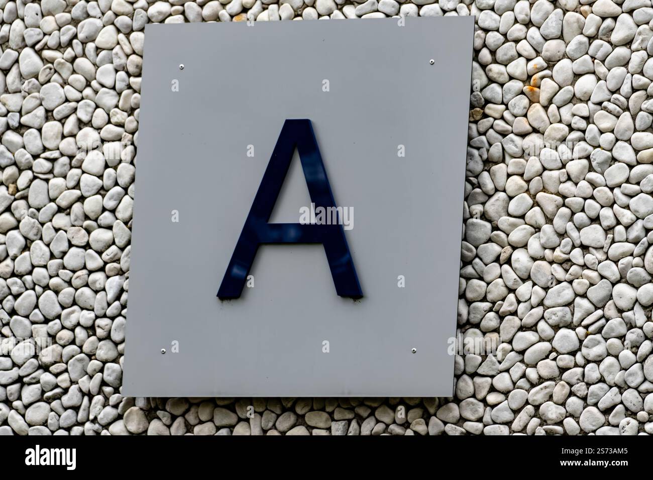 A square sign with the letter A on it. The sign is on a wall made of ...