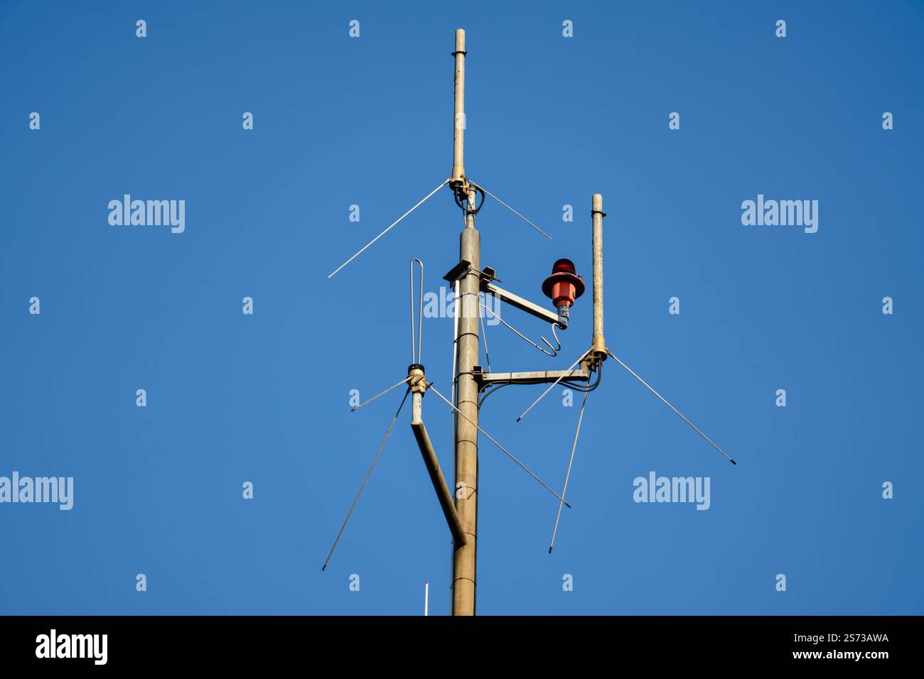 A tall pole with a red light on top. The pole is surrounded by wires ...