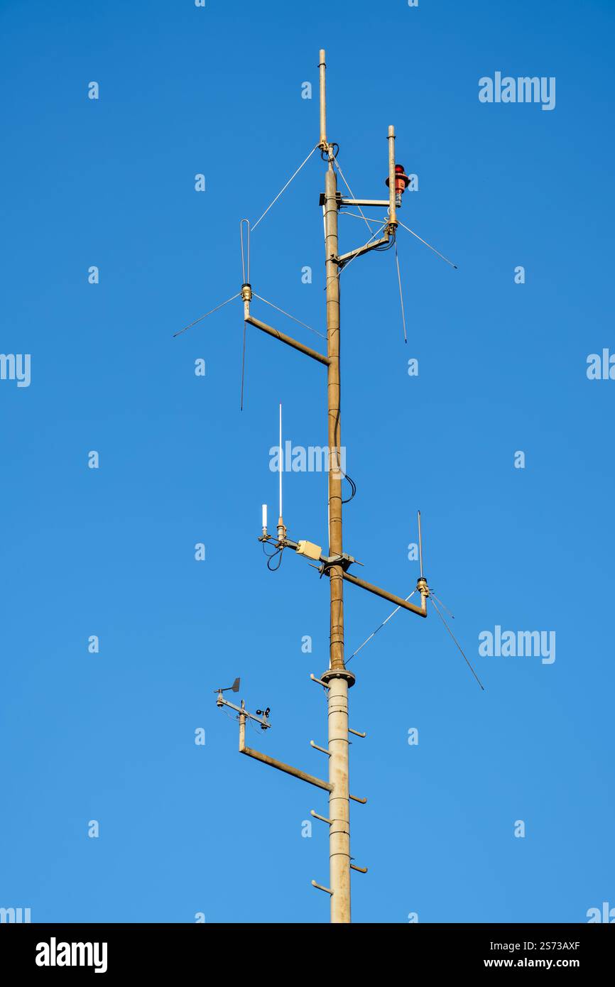 A tall pole with antennas on it is in the sky. The pole is surrounded ...