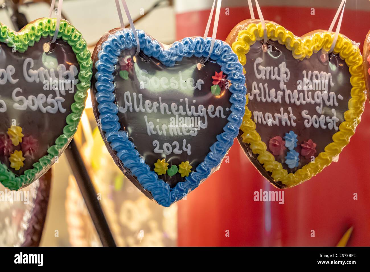 Three heart shaped cookies with writing on them. The cookies are ...