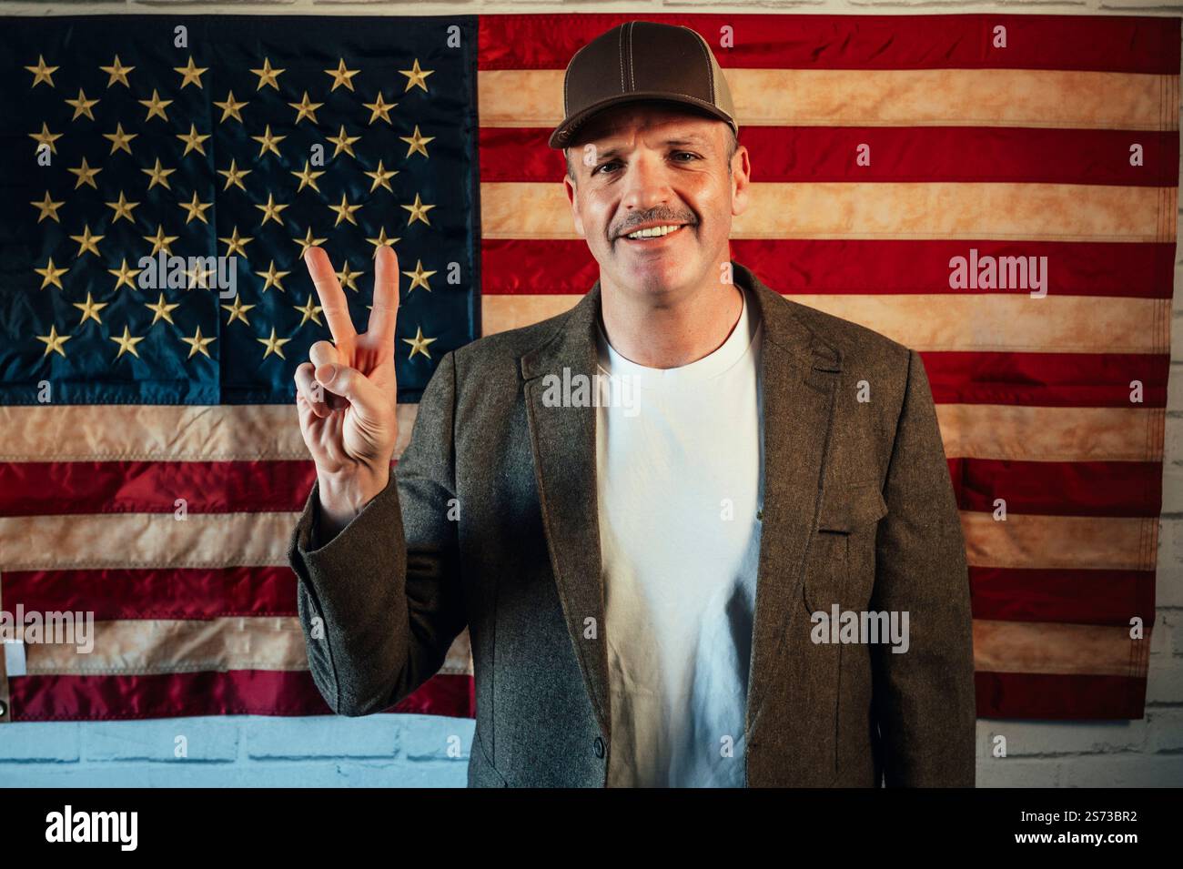 Man shows peace sign, standing before American flag Stock Photo - Alamy