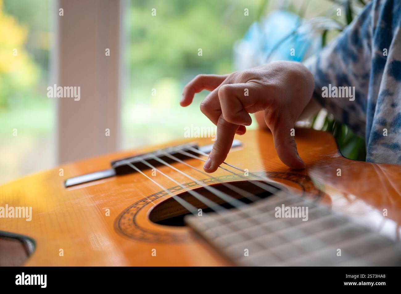 A closeup of fingers plucking strings on a classic acoustic guitar ...