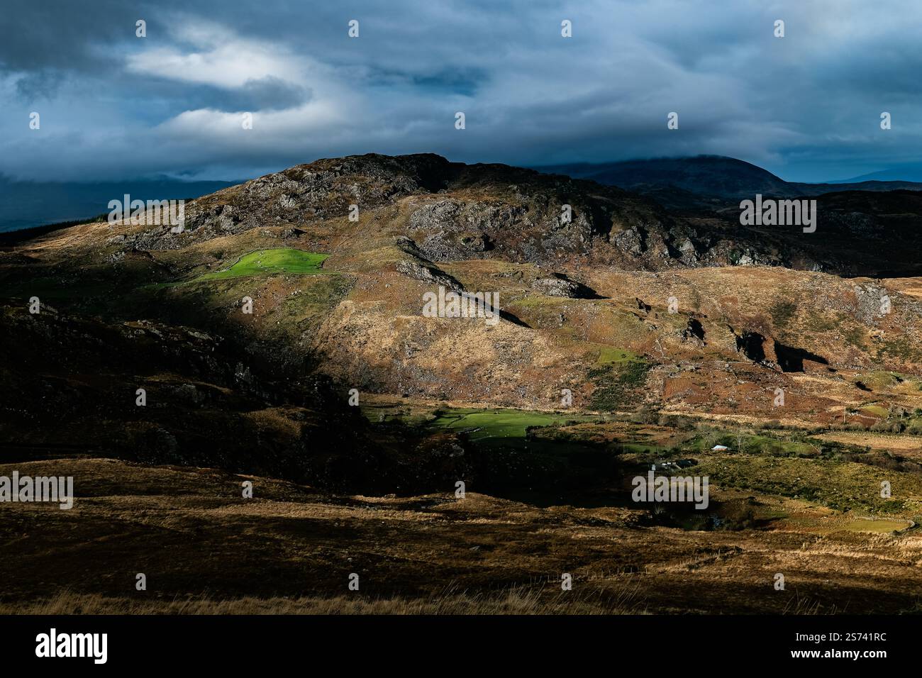 Dark clouds dominate the sky above a sprawling panorama of hills and ...