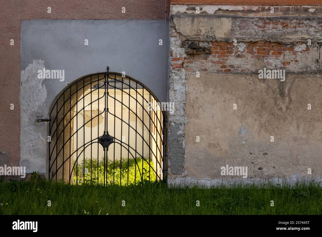 Old weathered bricks wall of a house. Arched closed gate with grid ...