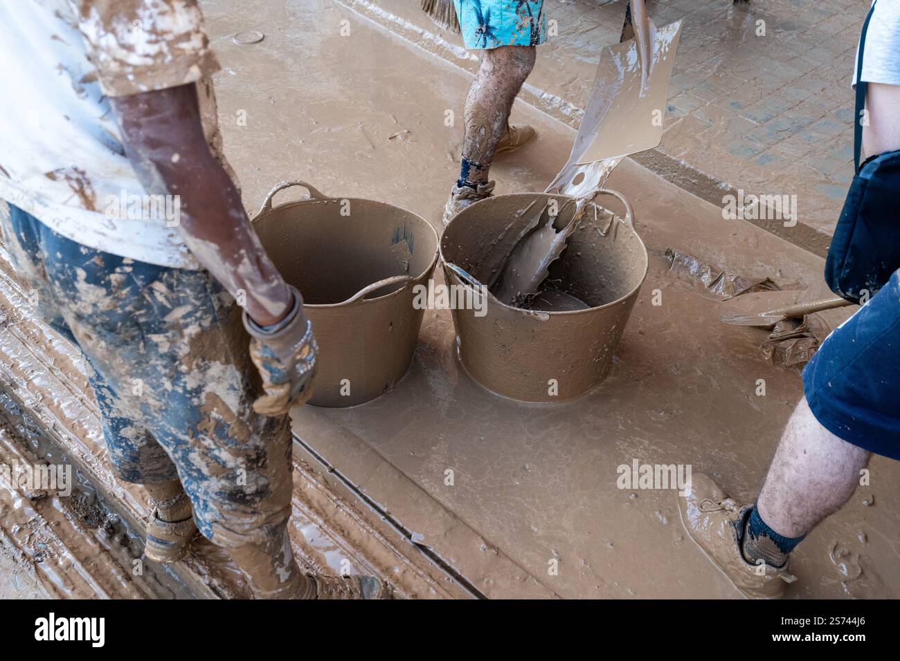 People covered in mud cleaning mud from the streets recollecting into ...