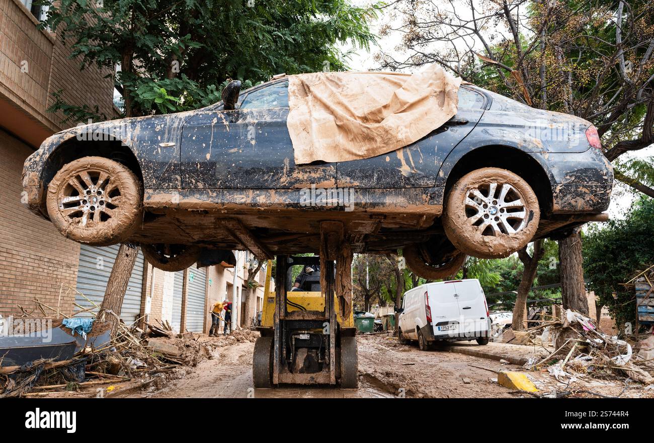 Ground view of a damaged car lifted by a fork lift in a muddy street ...