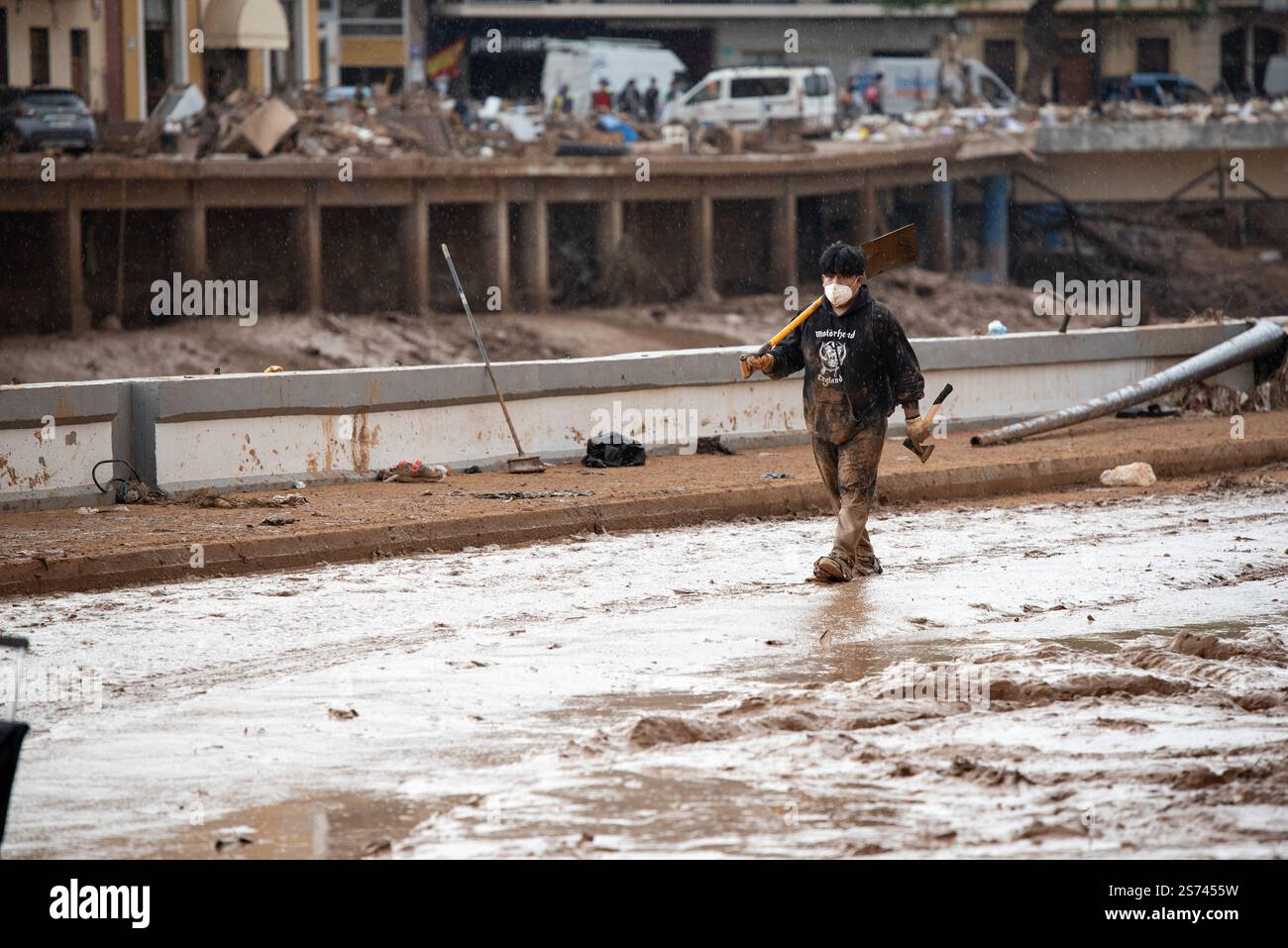 Young man with shovel axe and surgical mask walking in the mud in muddy ...