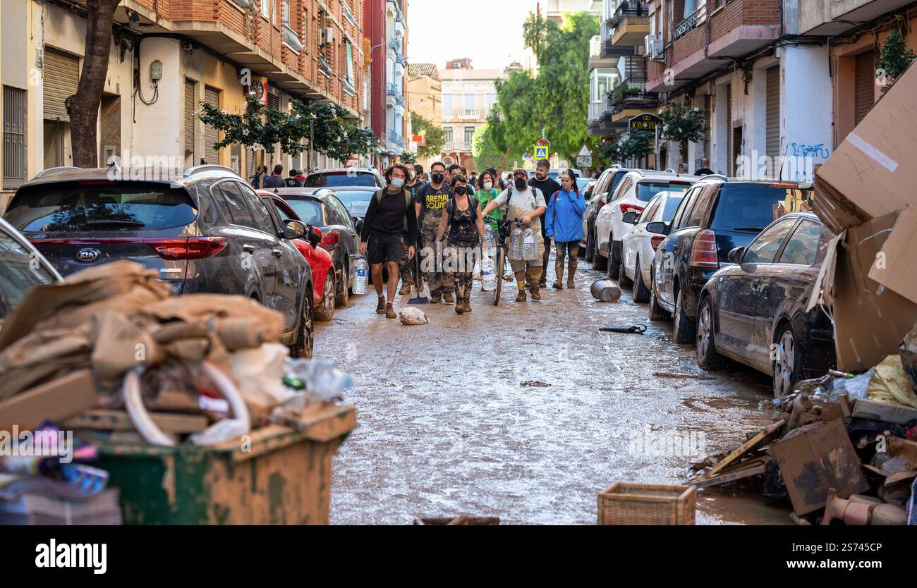 Group of people volunteers with 5 liter tanks of water in a muddy ...