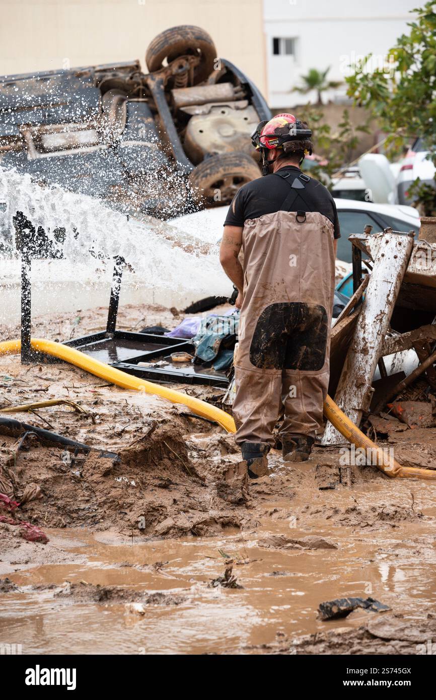 Unrecognizable firefighter in water resistant vest throws water with ...