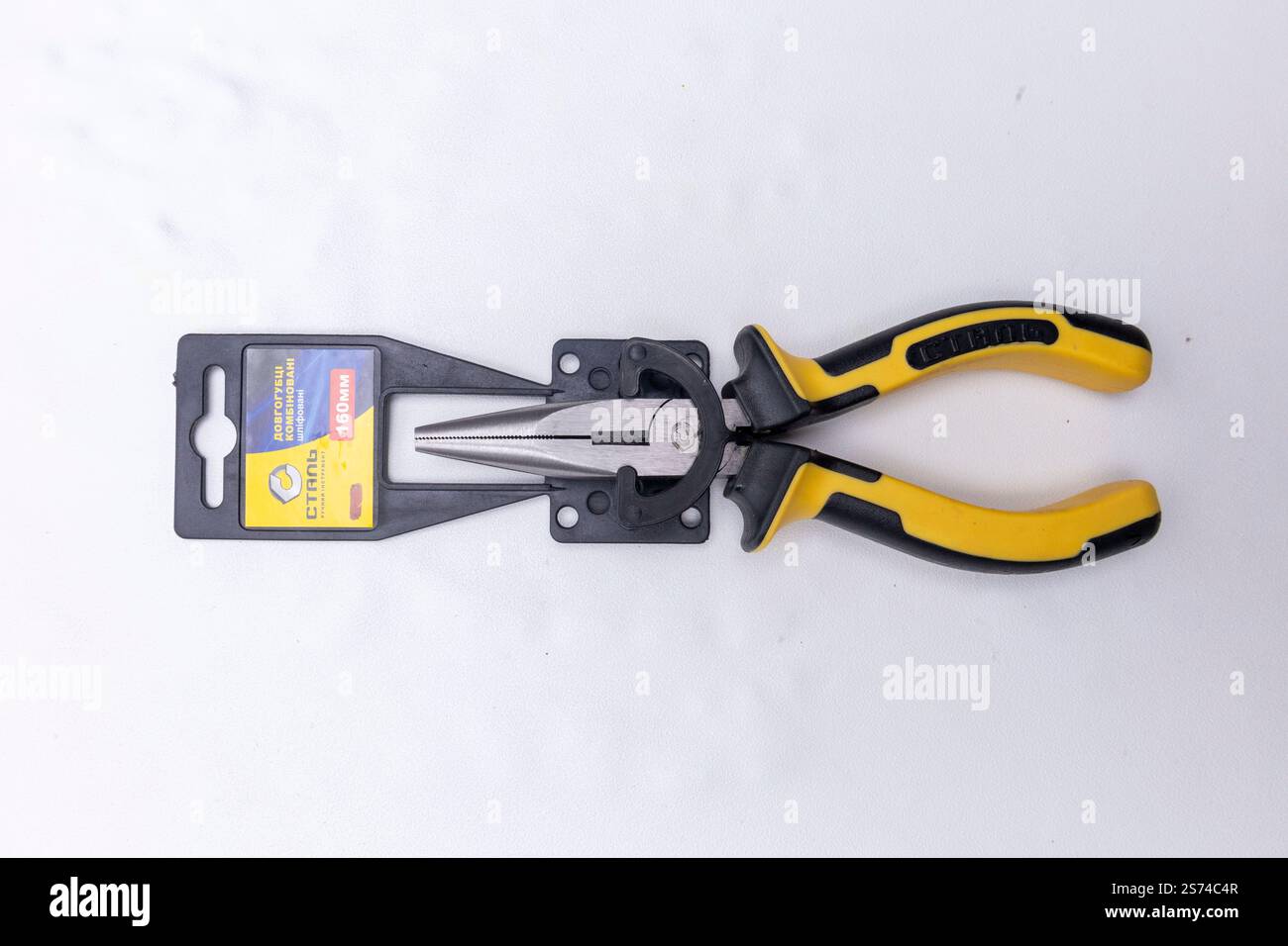Combination pliers with yellow and black plastic handles on white ...