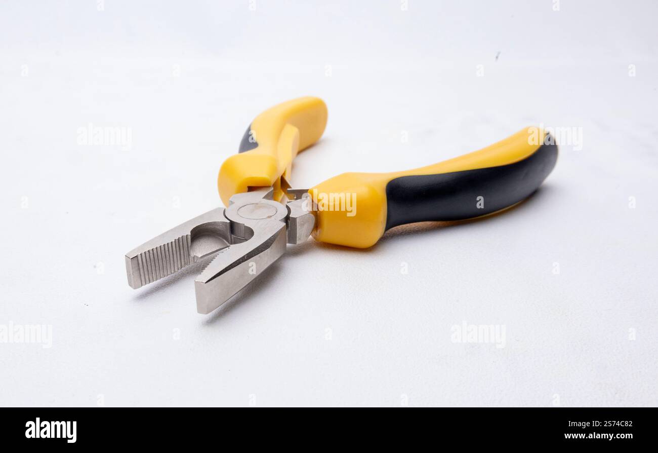 Combination pliers with yellow and black handles lying on a white ...