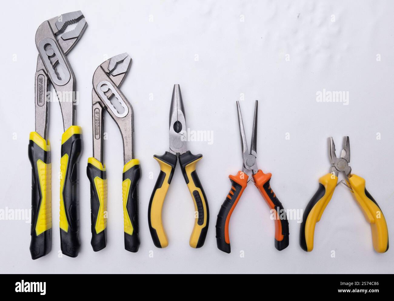 Different sizes of pliers and slip joint pliers lying on a white ...