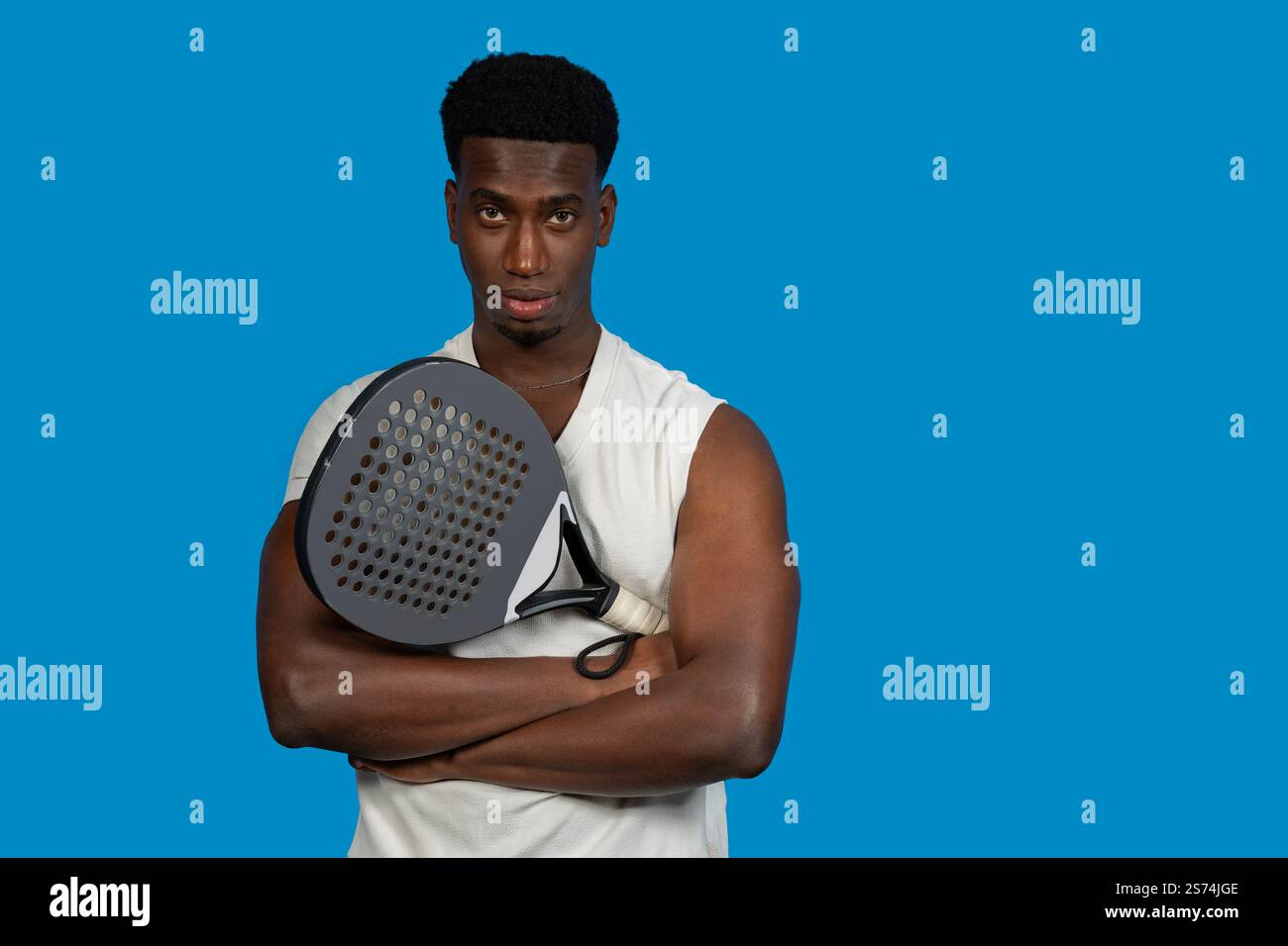 Confident male padel player holding racket with crossed arms, ready for ...