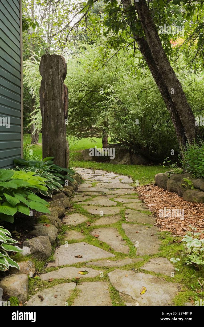 Jack rabbit Johanssen wooden totem pole, flagstone path next to border ...