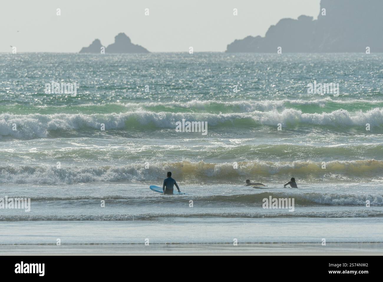 A group of people are surfing in the ocean. The water is choppy and the ...