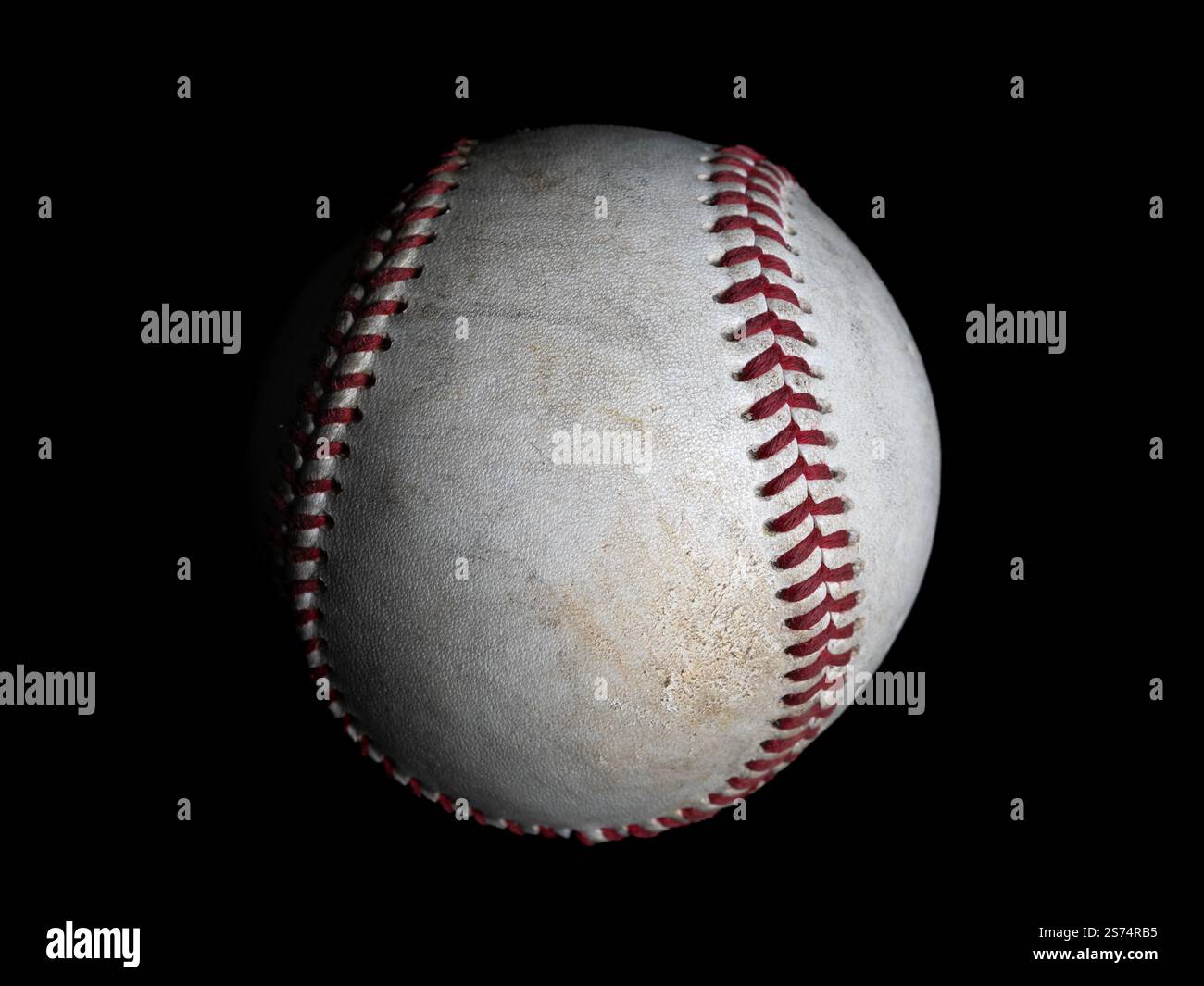 A single baseball viewed from the side, isolated on a deep black ...