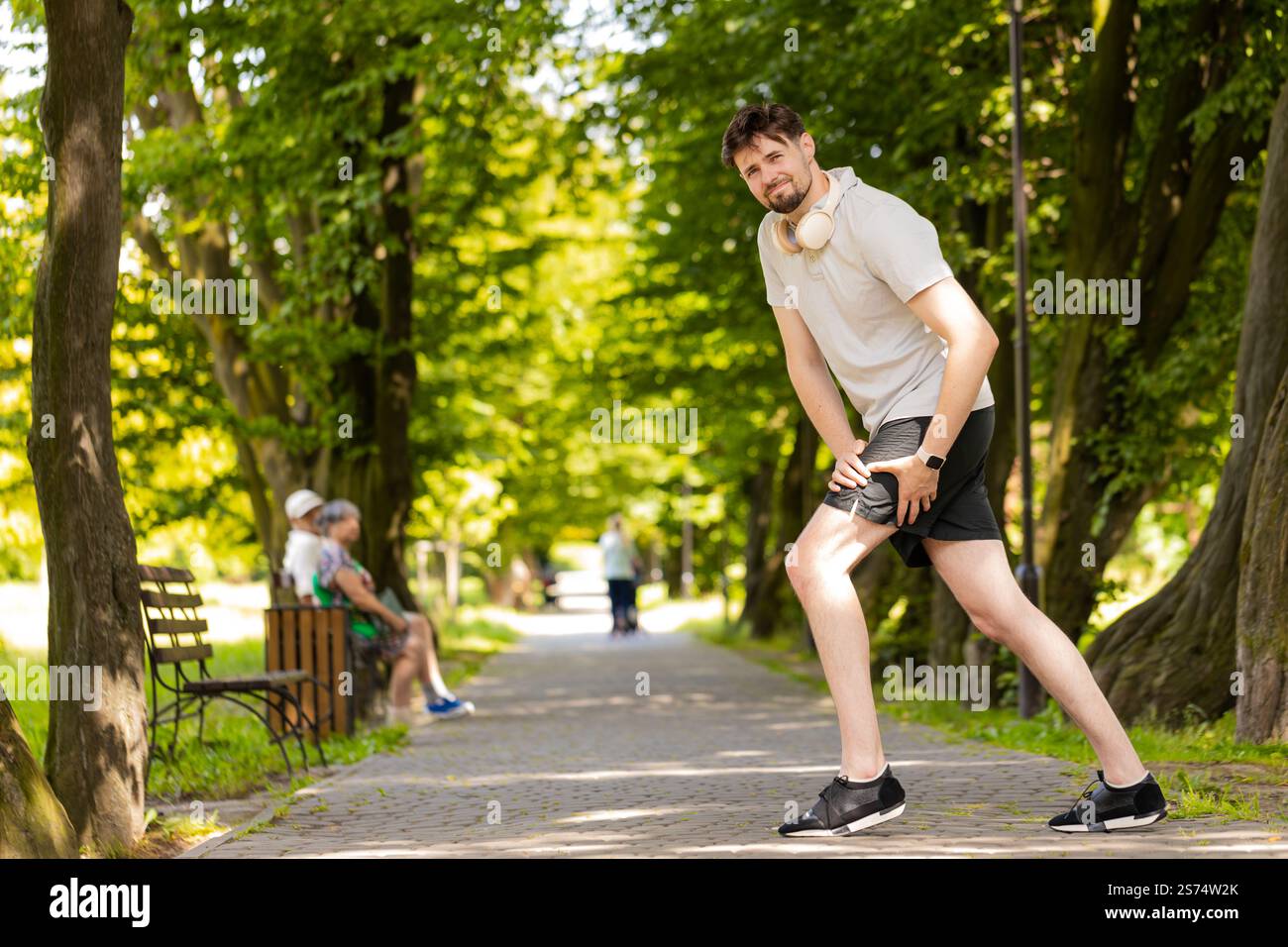 Young runner athlete with muscle pain. Man in shorts massaging ...