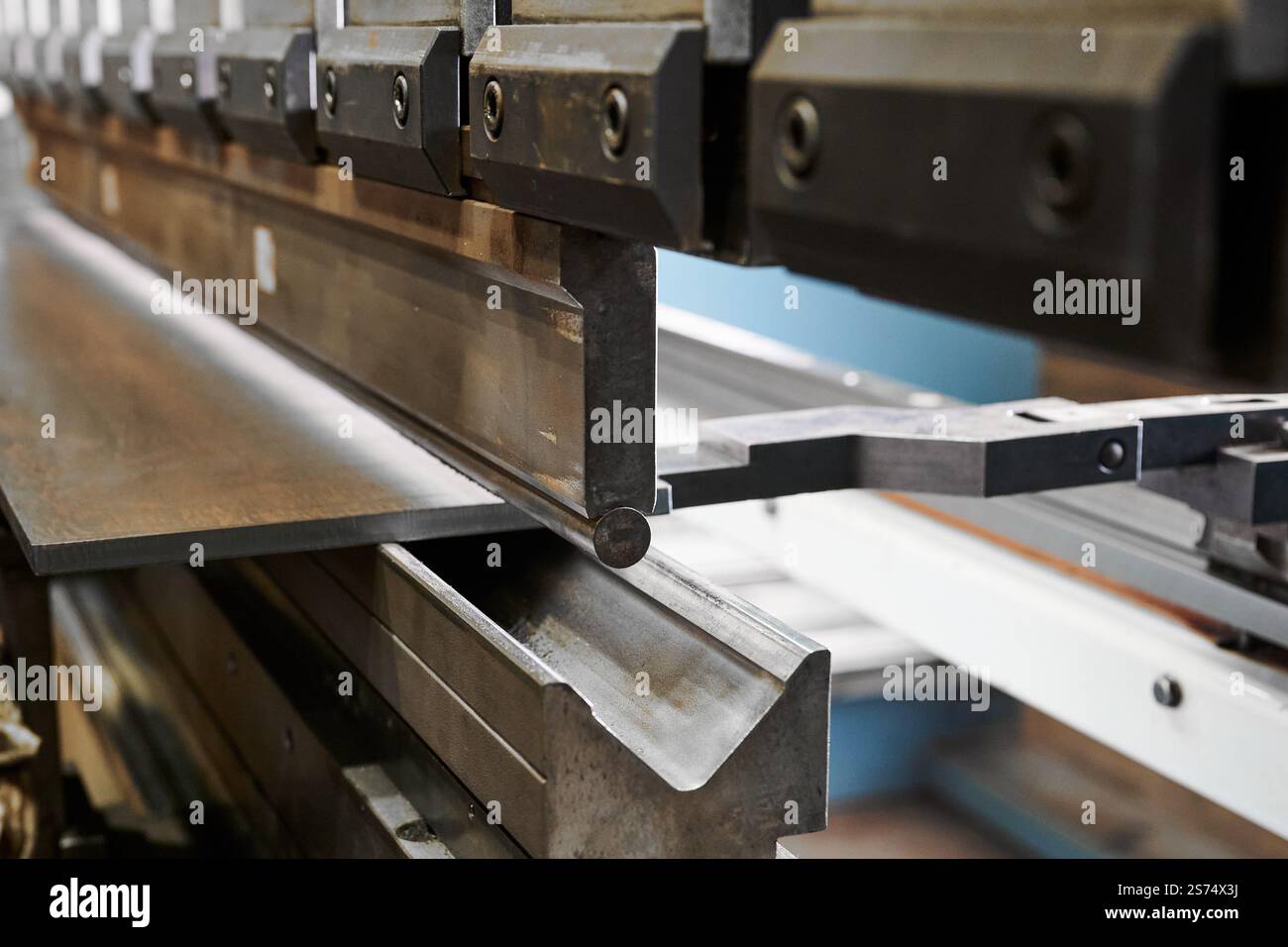 Bending machine operates with heavy metal plate in shop Stock Photo - Alamy