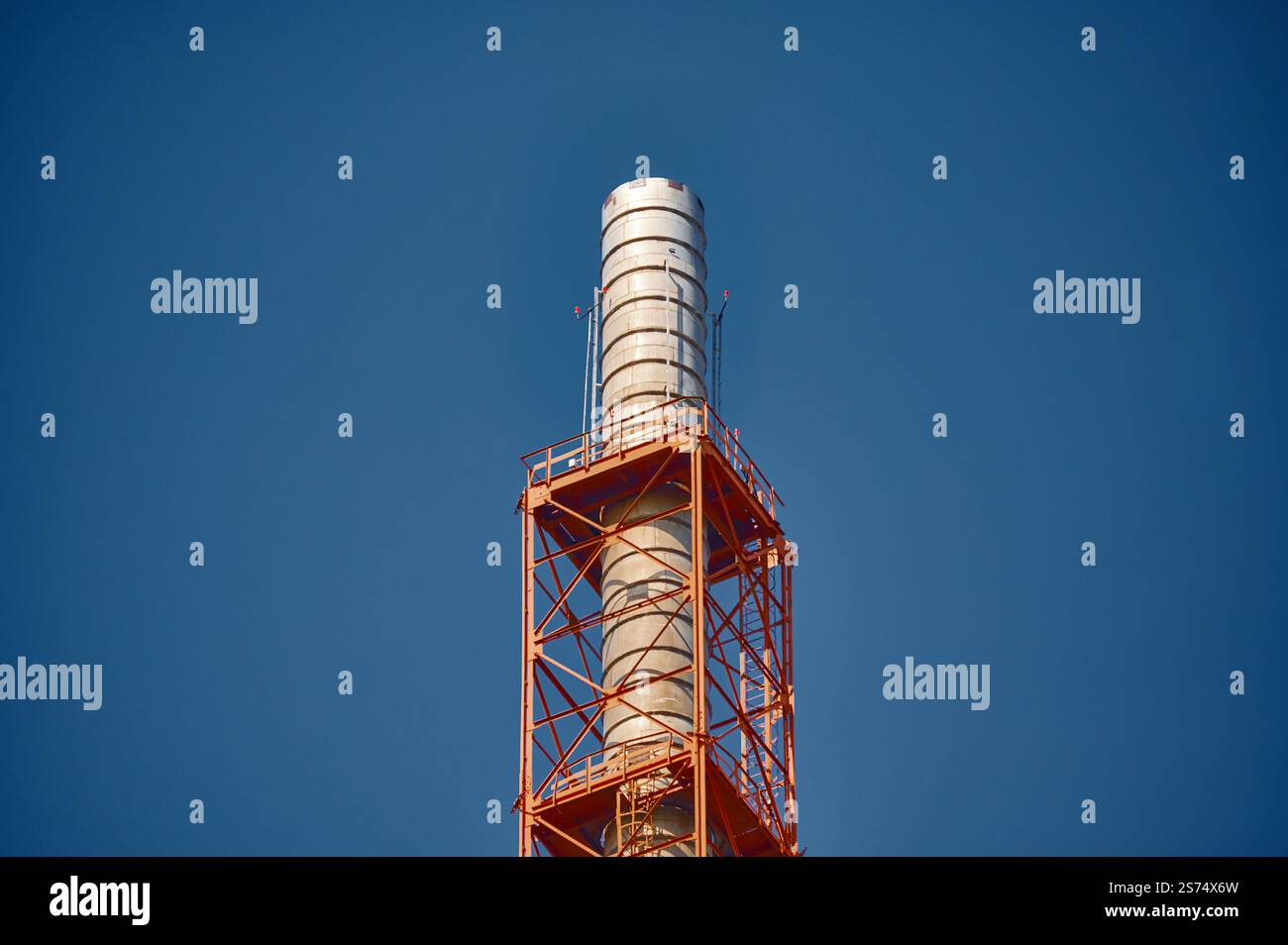 High distillation column rising above a chemical plant under a clear ...