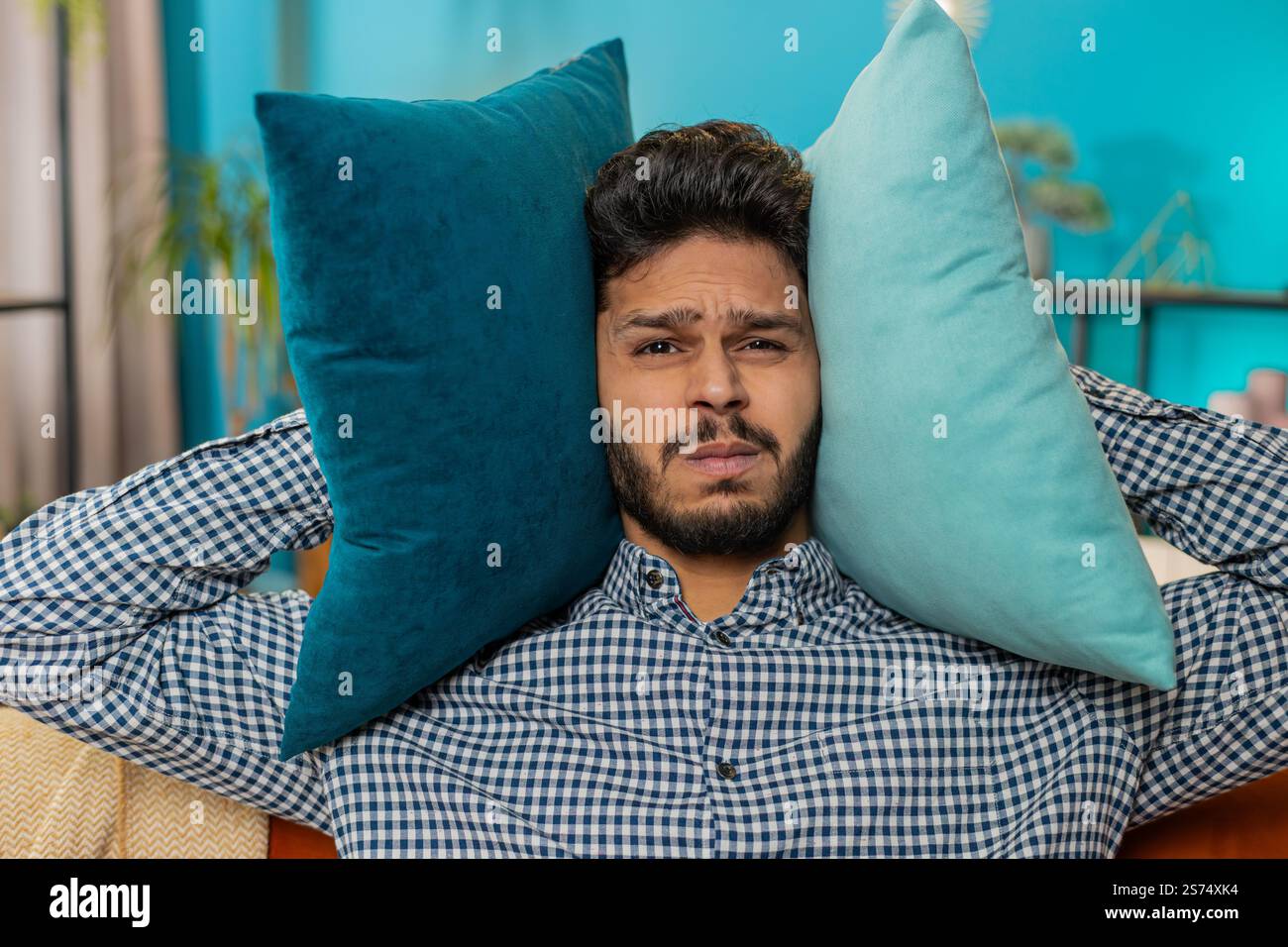 Repair work at neighbors. Irritated Indian young man cover ears with ...