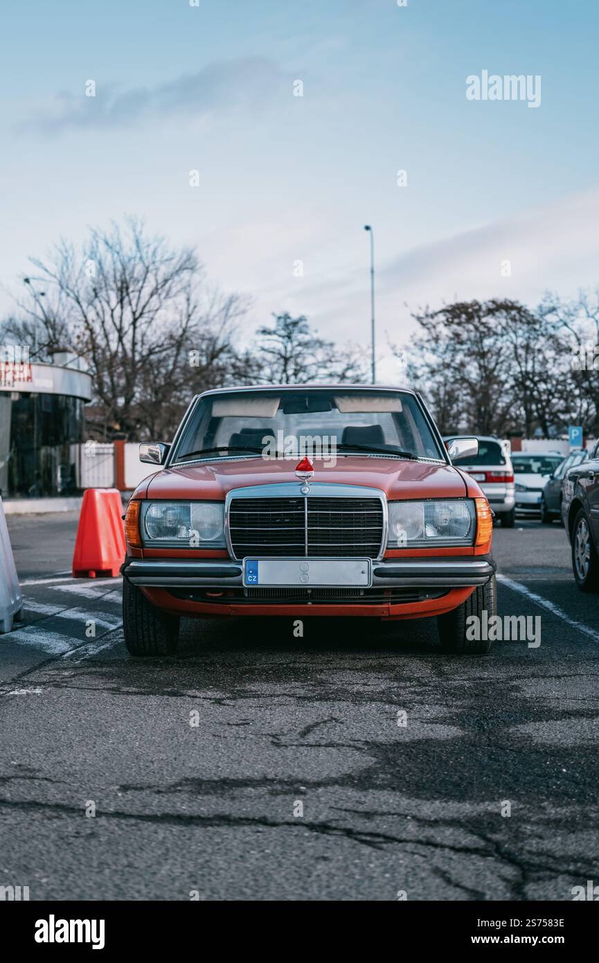 Front view of a classic orange Mercedes-Benz W123 sedan parked outdoors ...
