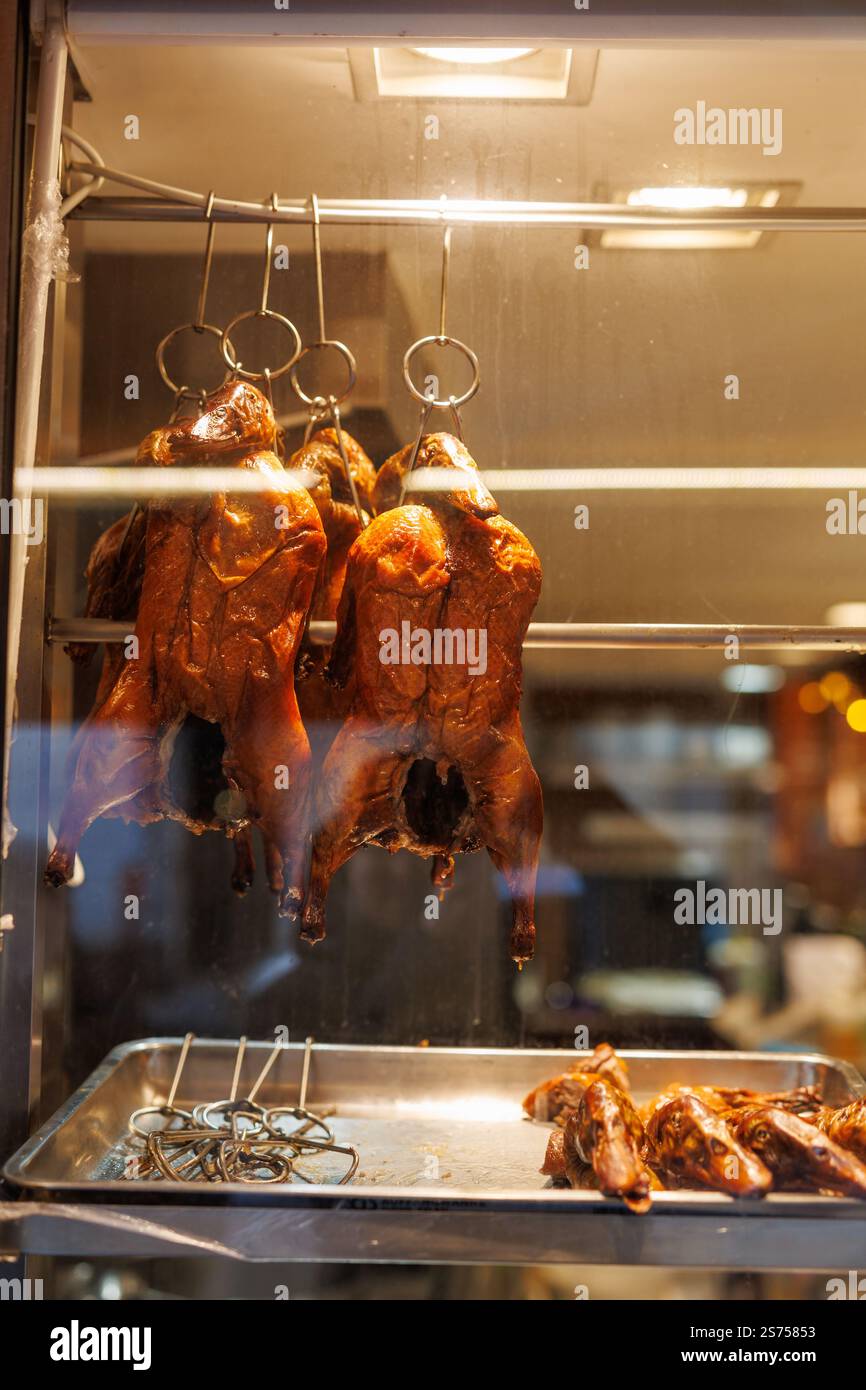 Close-up of roasted ducks hanging in a display case with additional ...