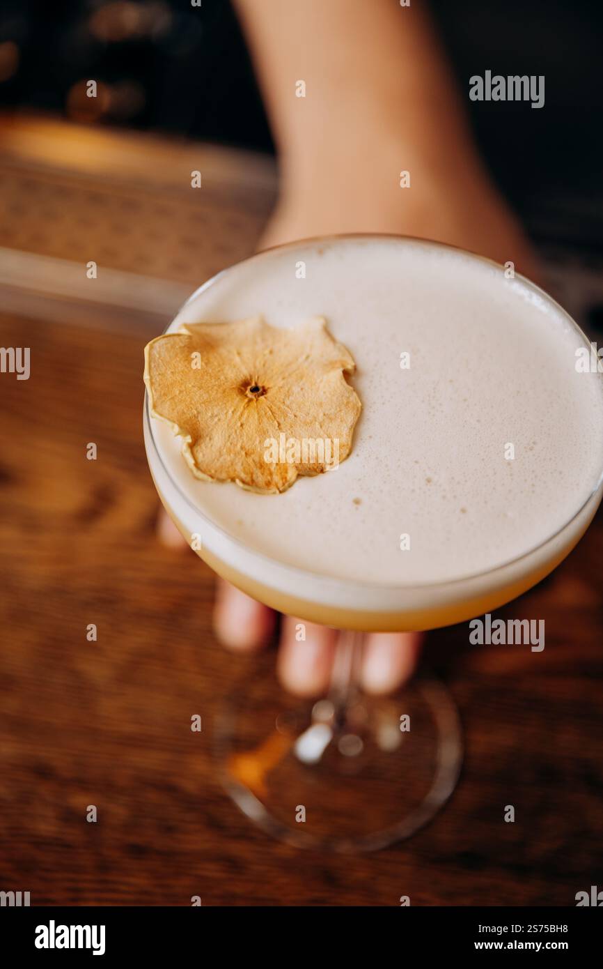 Bartender presenting a crafted cocktail with a dried fruit garnish in ...