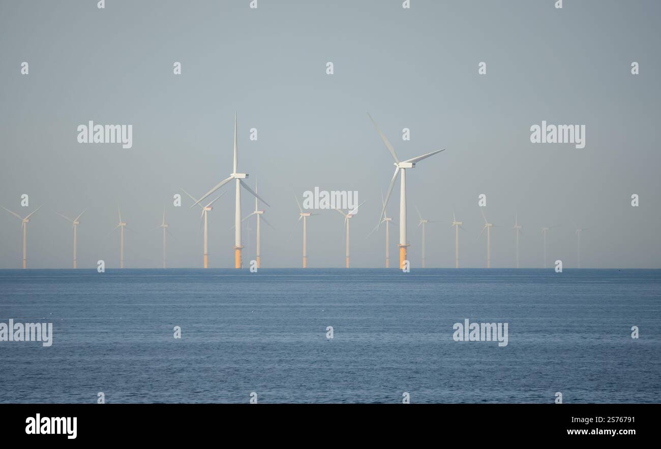 tens of tall wind turbines of an offshore wind farm, in action, Gwynt y ...