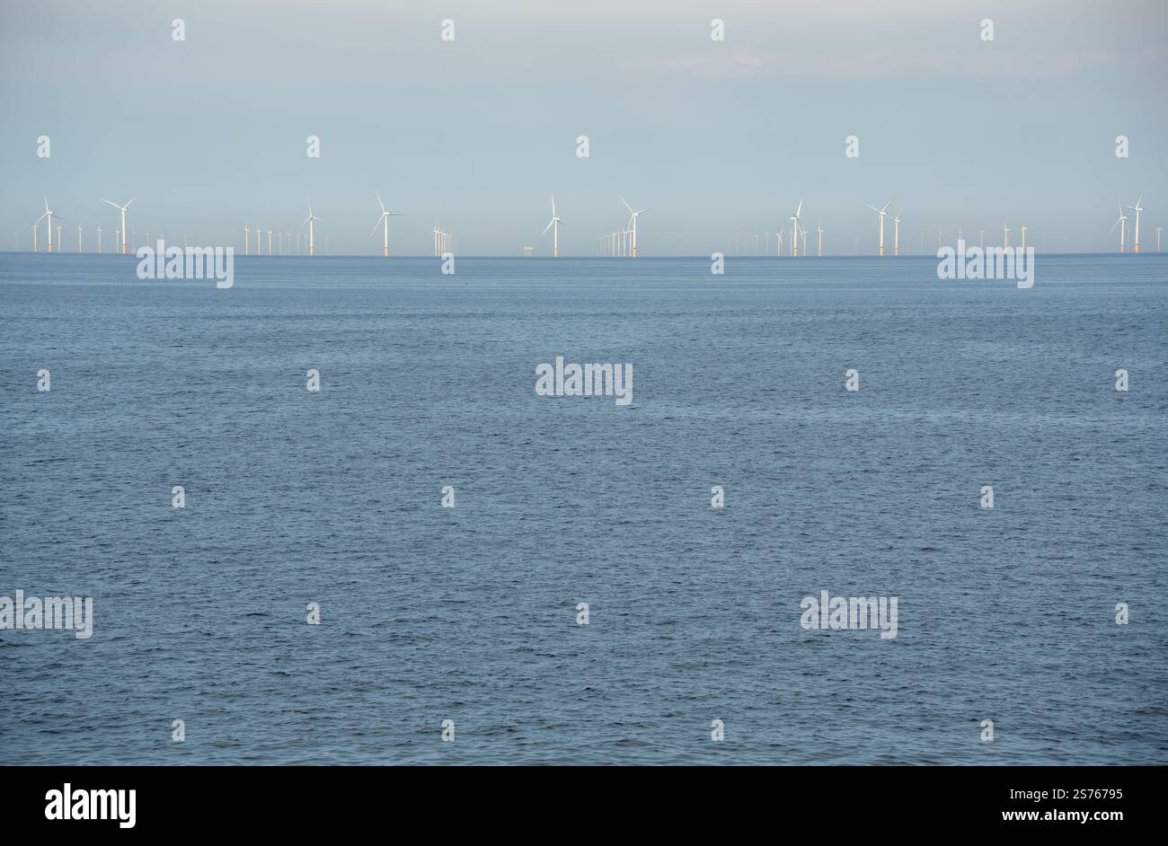 tens of tall wind turbines of an offshore wind farm, in action, Gwynt y ...