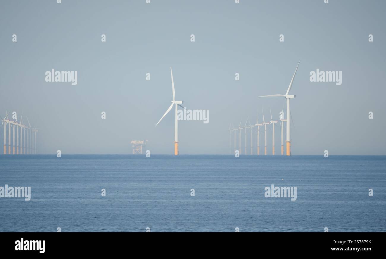 tens of tall wind turbines of an offshore wind farm, in action, Gwynt y ...