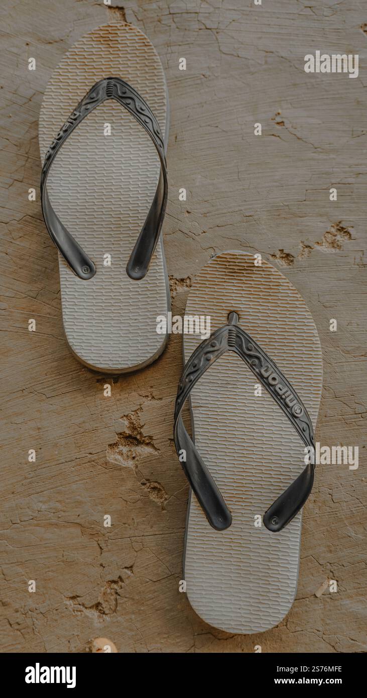 A pair of worn flip flops on a textured, cracked surface Stock Photo ...