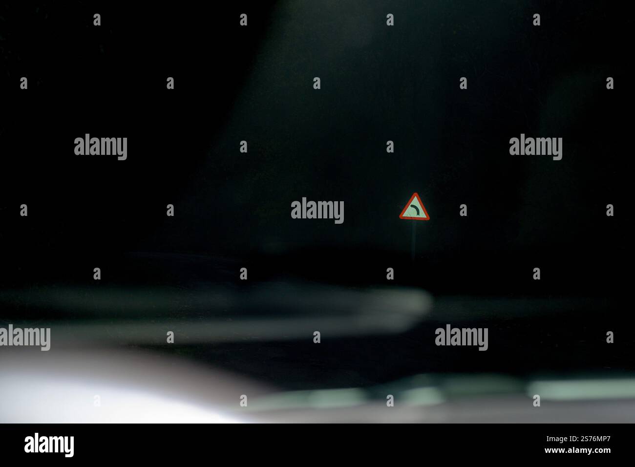 Dangerous curve sign from inside the car at night Stock Photo - Alamy