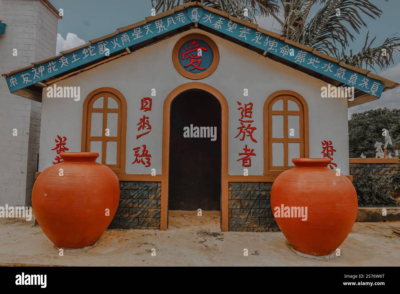 A small, traditional Asian-style building with large red pots in front ...