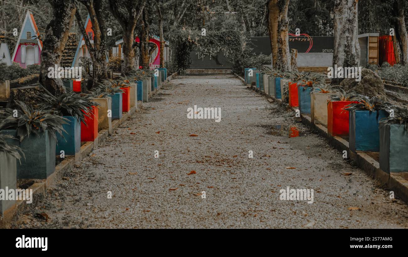 A serene pathway lined with colorful planters and trees in a park ...