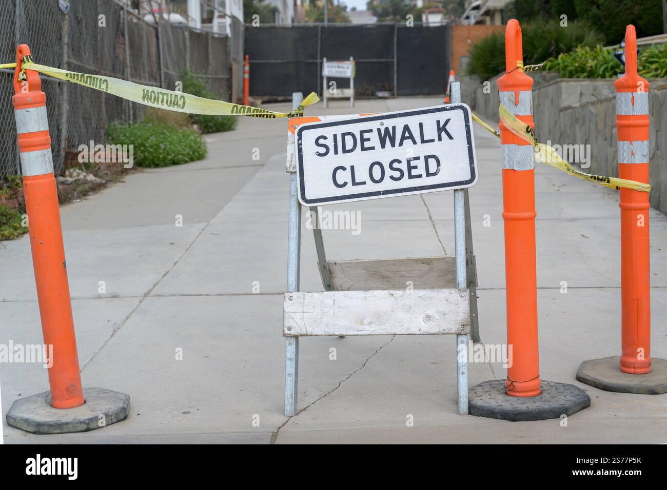 Sidewalk closed sign with three orange plastic bollards and yellow ...