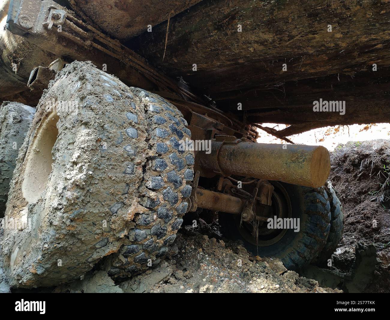 A close-up view of a muddy tire stuck under a large structure ...