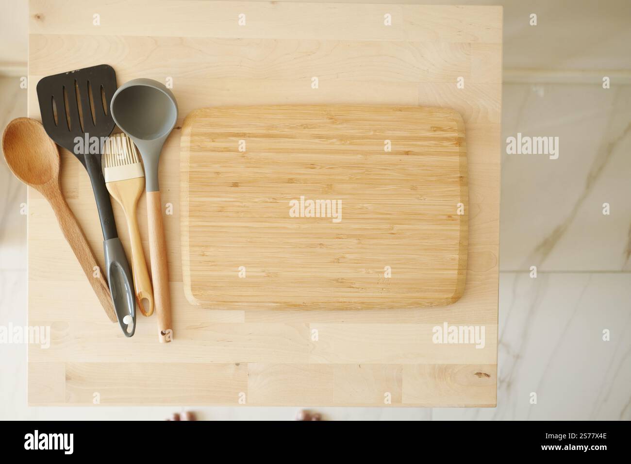 Various kitchen utensils and a cutting board are on the countertop ...