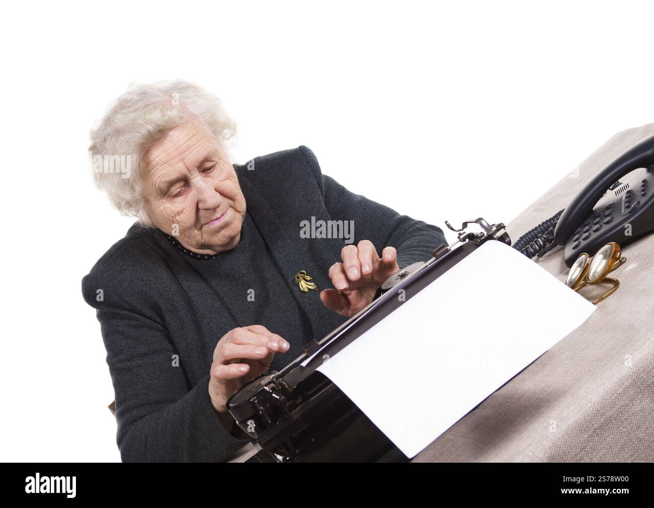 Old woman typing on an old typewriter against a white background ...