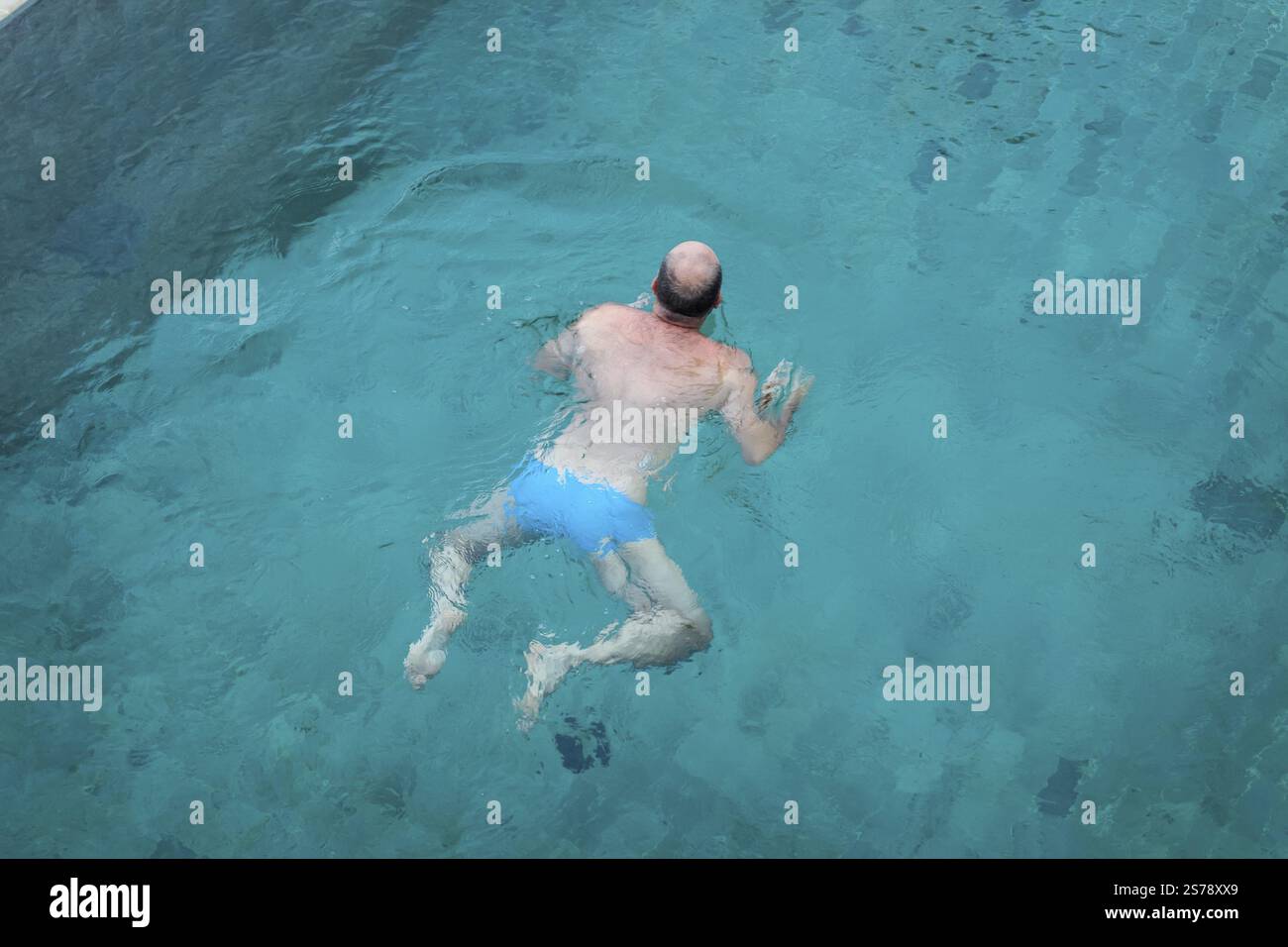 Balding man swimming in clean turquoise blue water viewed from above in ...