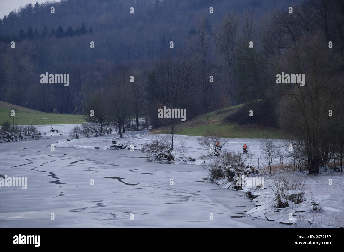 Cyclist on icy cycle path around the Gnadental reservoir, Sailach ...