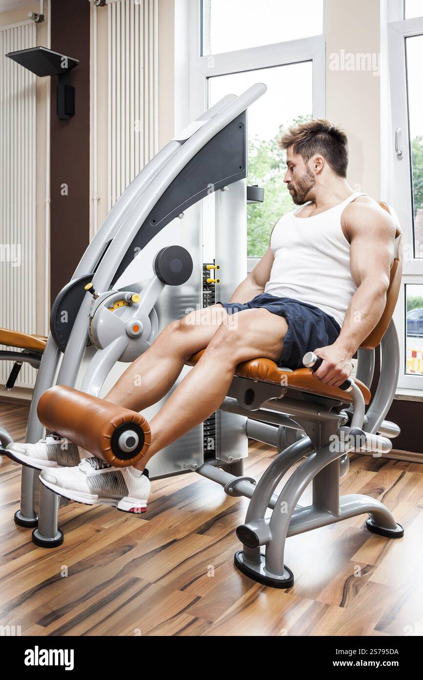A handsome young muscular sports man doing leg press Stock Photo - Alamy