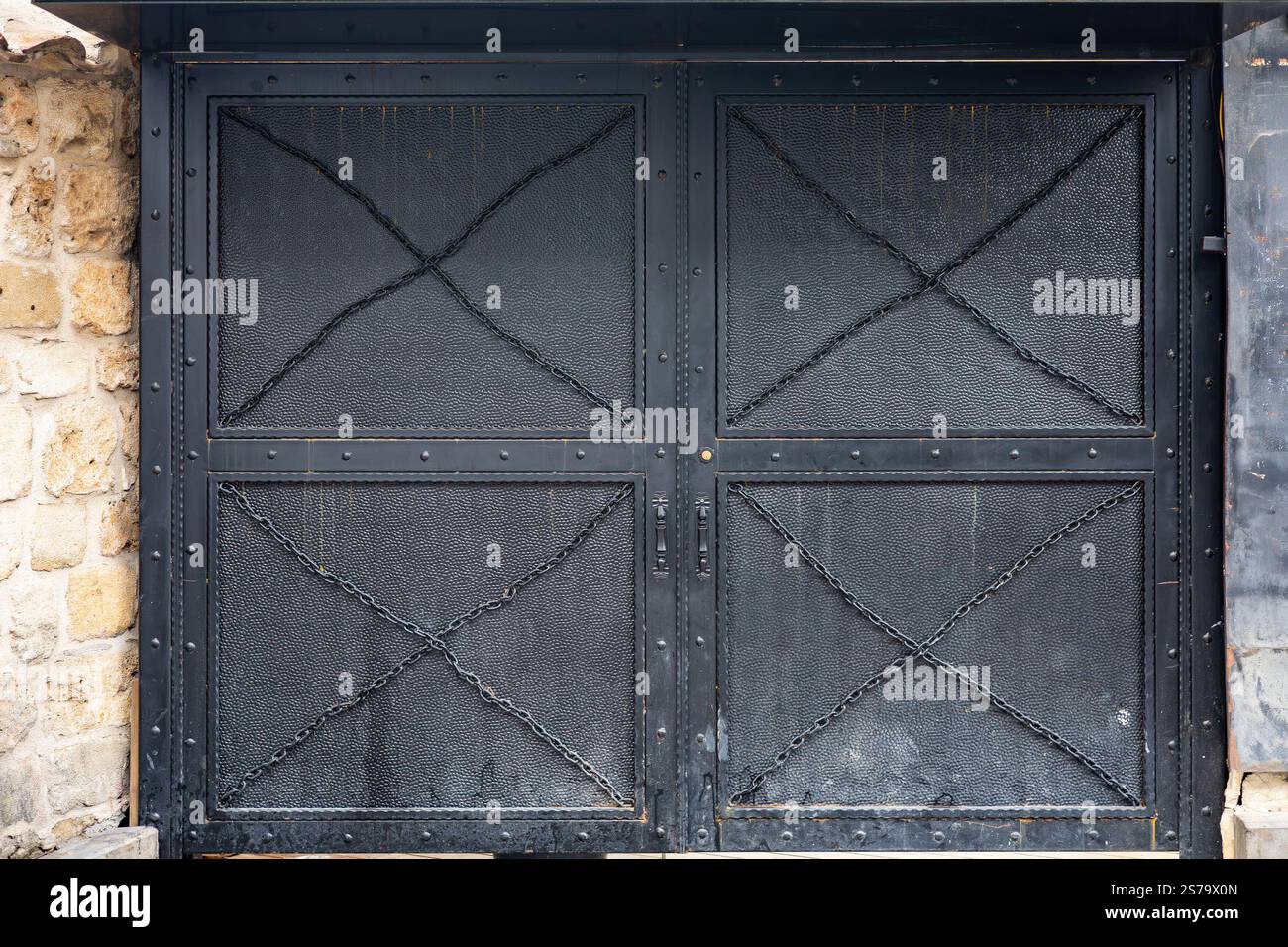 Rustic black metal gate with stone wall backdrop Stock Photo - Alamy
